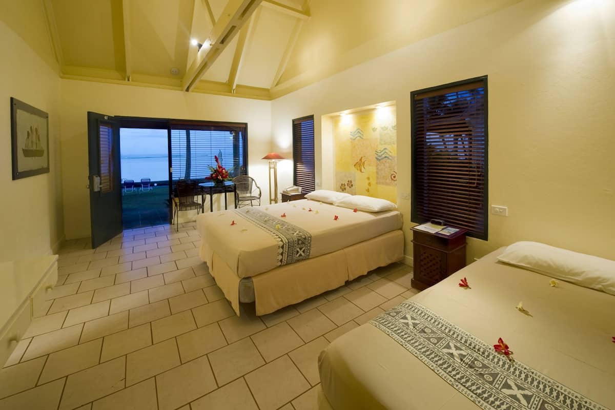 Quarto de hotel com cama, secretária e vista para o mar.