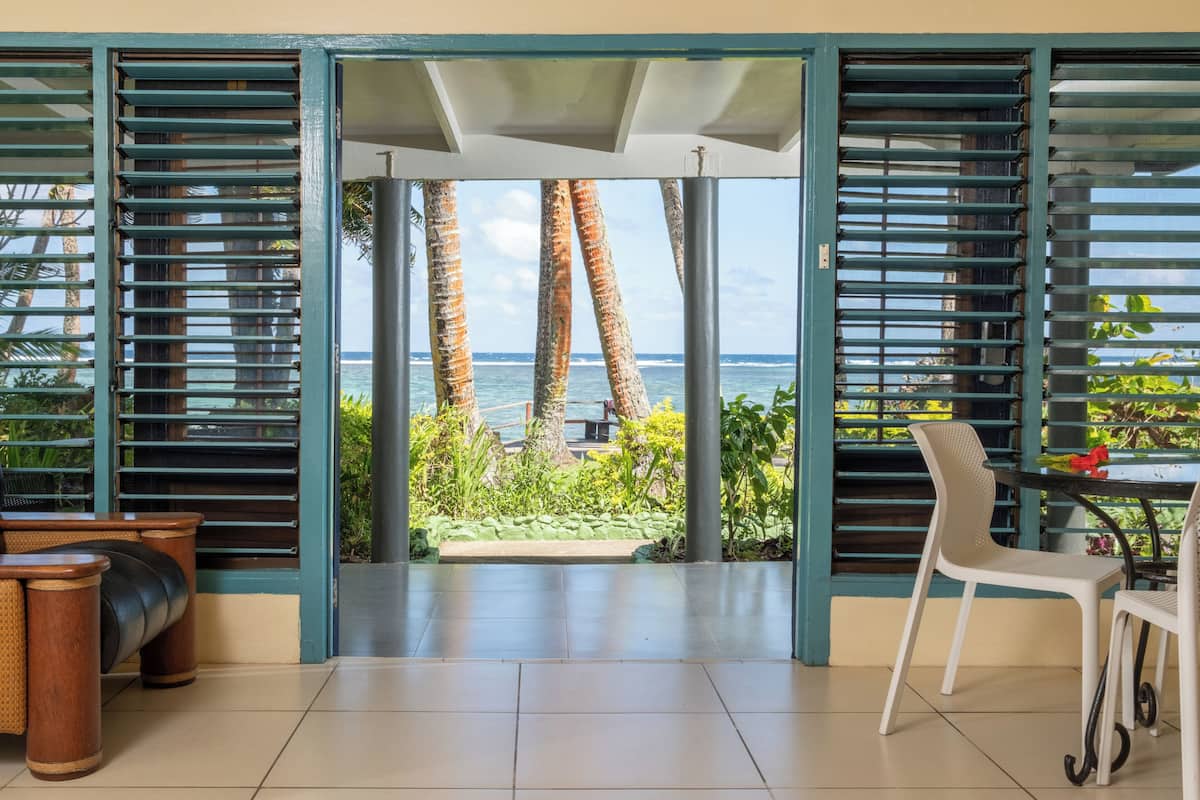 Quarto com vista para o oceano, uma mesa com cadeiras e um banco.