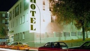 A building with a prominent "HOTEL" sign on its facade, featuring multiple windows and a balcony.