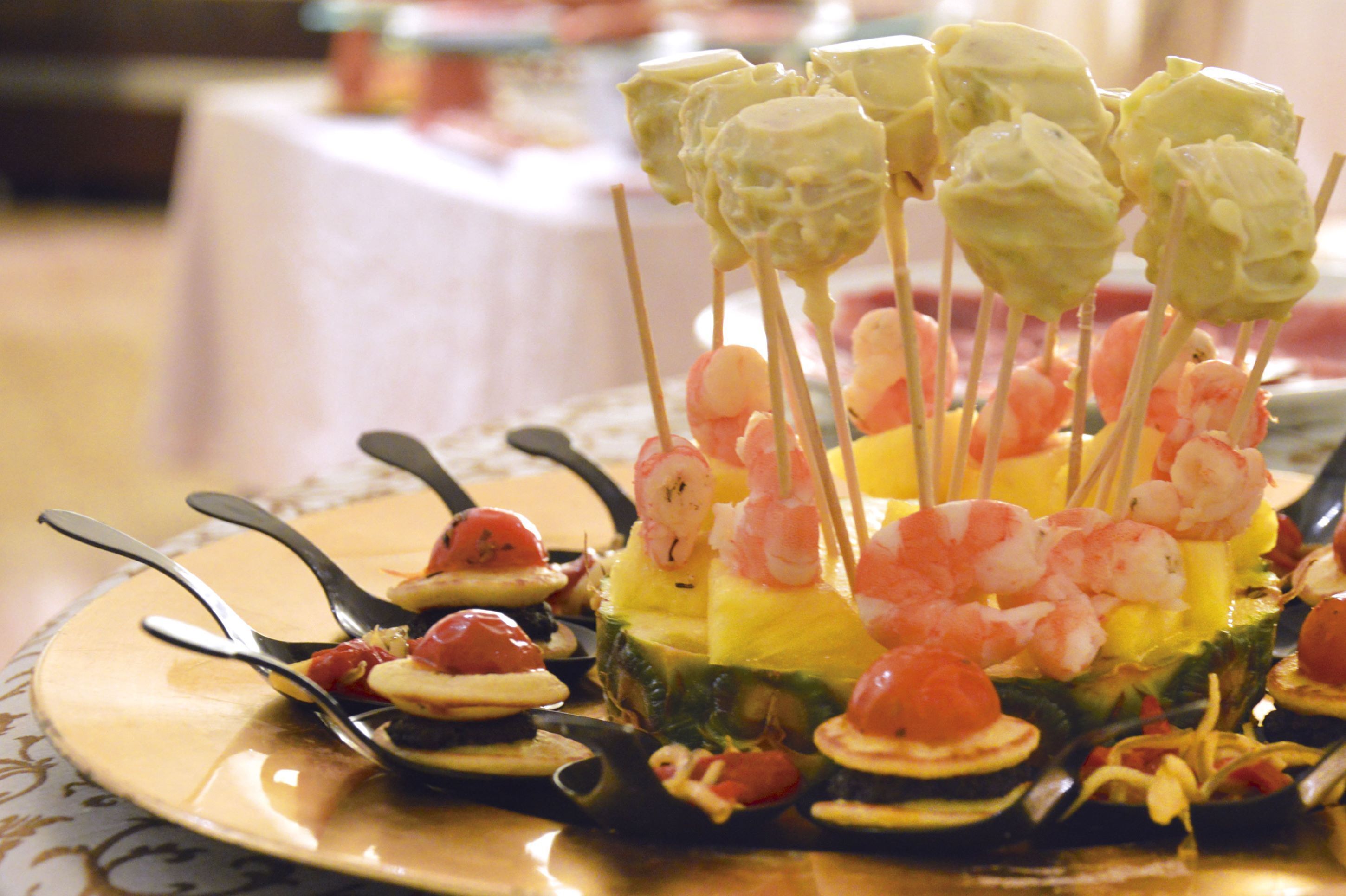 Prato de petiscos com espetinhos de camarão, bolinhas de queijo e pequenos frutos do mar.