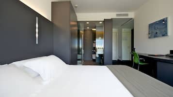 Quarto de hotel moderno com uma cama grande, uma escrivaninha e um espelho.