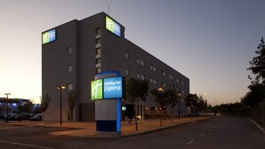 Edifício Holiday Inn Express com uma placa grande, um estacionamento e um céu claro.