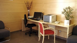 Um espaço de trabalho com escrivaninha, computador, impressora e duas cadeiras.