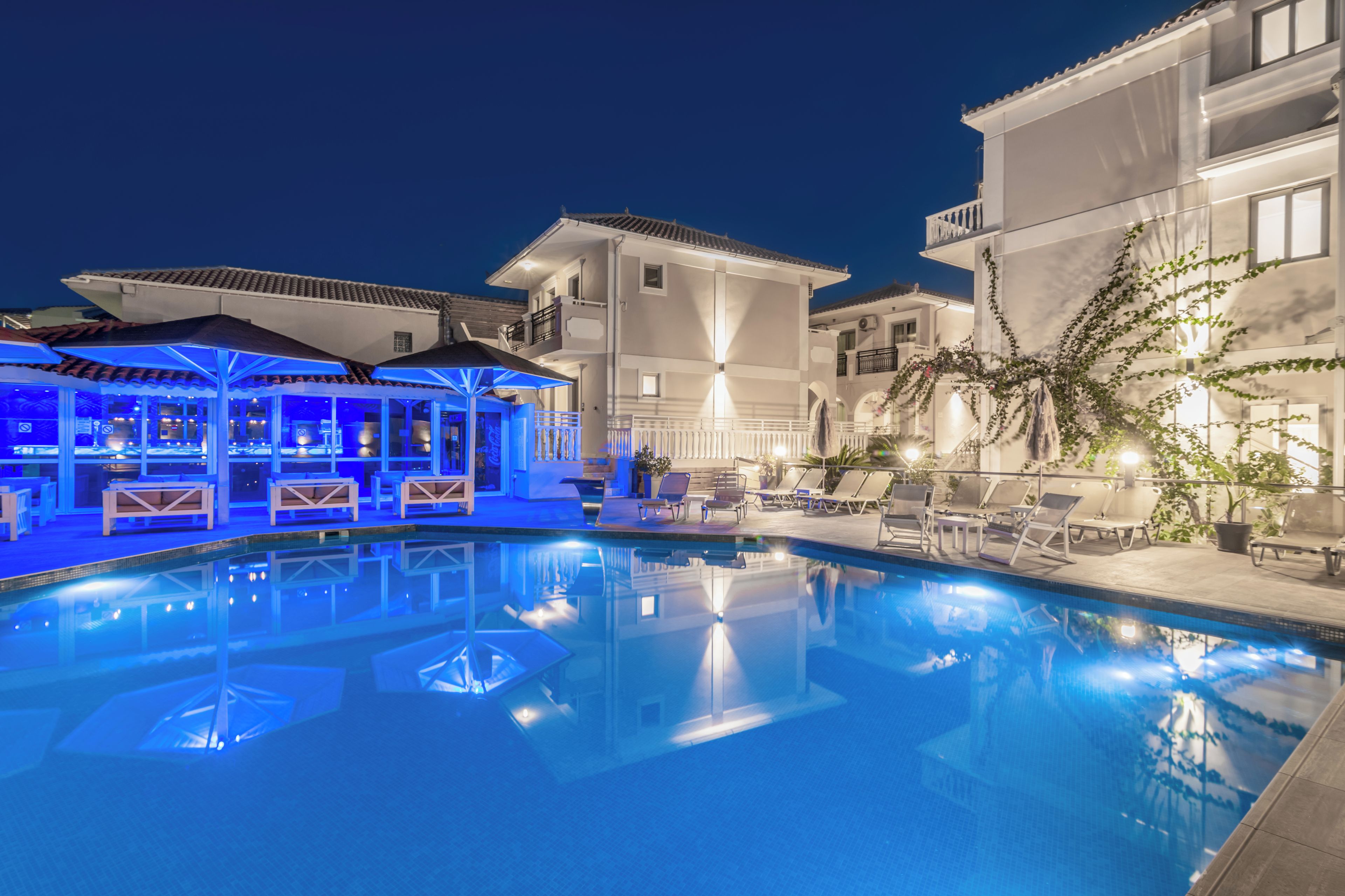 Piscina com espreguiçadeiras e área de bar com iluminação azul.