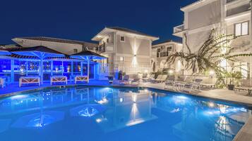Piscina com espreguiçadeiras e área de bar com iluminação azul.