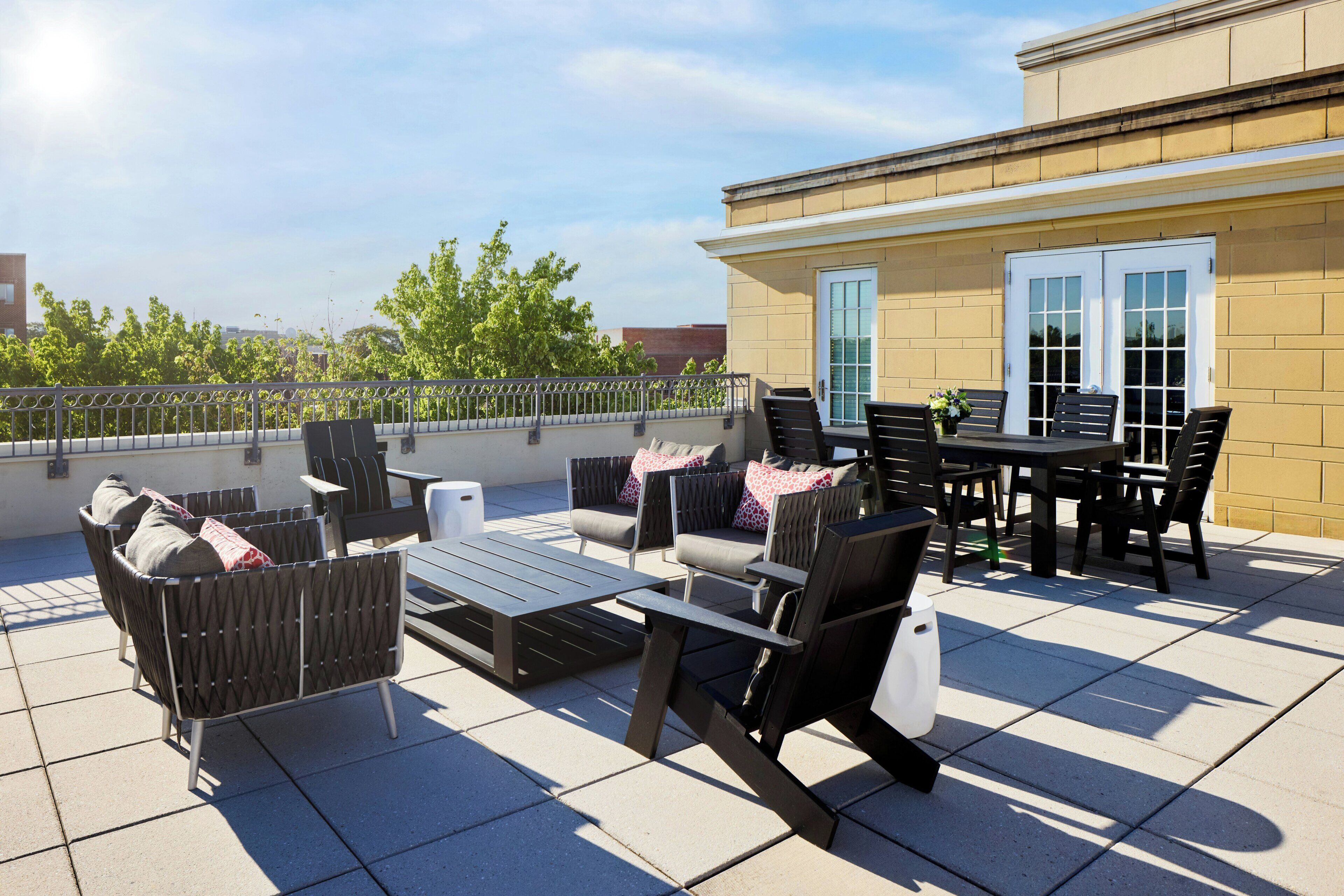 Um terraço no telhado com mobiliário de exterior, uma mesa e vista para a paisagem urbana.