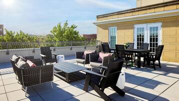Um terraço no telhado com mobiliário de exterior, uma mesa e vista para a paisagem urbana.