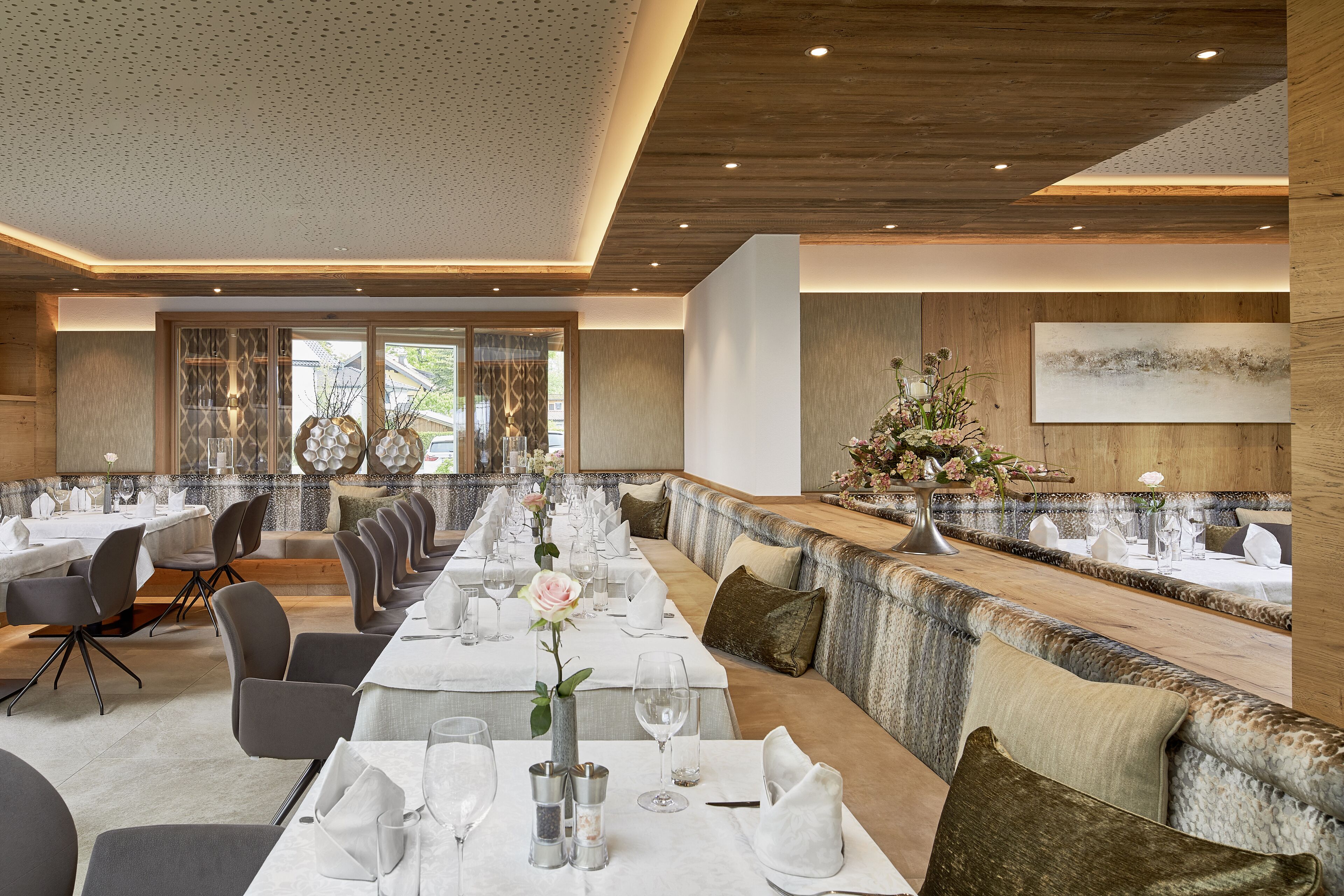Um restaurante com uma mesa de jantar comprida, várias cadeiras e um banco de encosto alto.