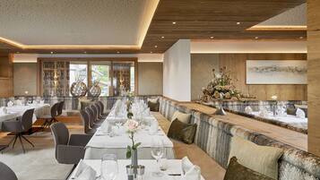 Um restaurante com uma mesa de jantar comprida, várias cadeiras e um banco de encosto alto.
