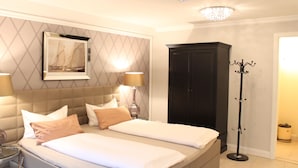 Quarto de hotel com duas camas, um espelho grande, um guarda-roupa e um abajur.