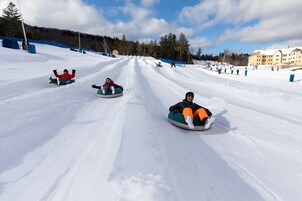 Pista de tobogã nevado com pessoas escorregando.