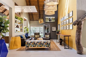Uma sala de estar moderna com sofá, poltronas, mesa de centro e uma janela grande com vista para árvores.