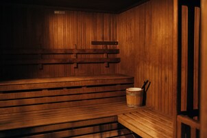 Uma sauna com bancos de madeira e um balde de madeira.