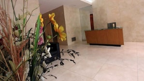 Uma área de recepção com uma mesa de madeira, um espelho grande e um vaso com flores.