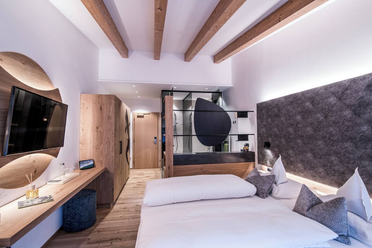 Quarto moderno com cama, mesa de cabeceira e um espelho grande.