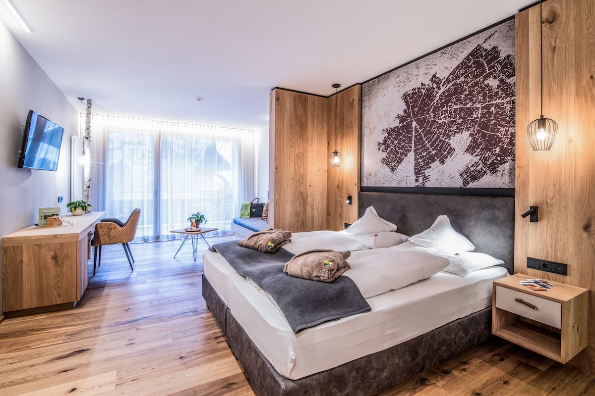 Quarto moderno com uma cama grande, cabeceira de madeira e uma obra de arte com paisagem urbana.