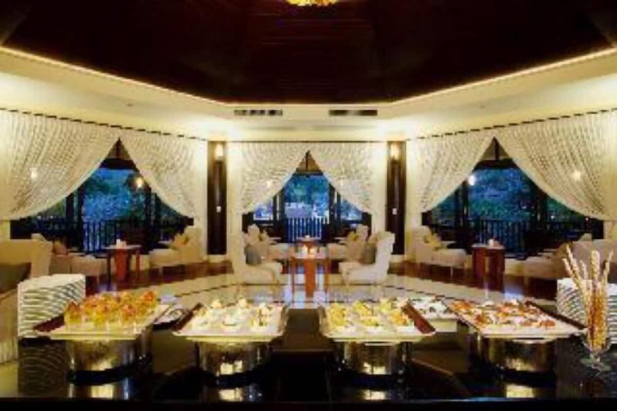 Uma sala de jantar luxuosa, com uma mesa central, sofás ao redor e um amplo buffet.