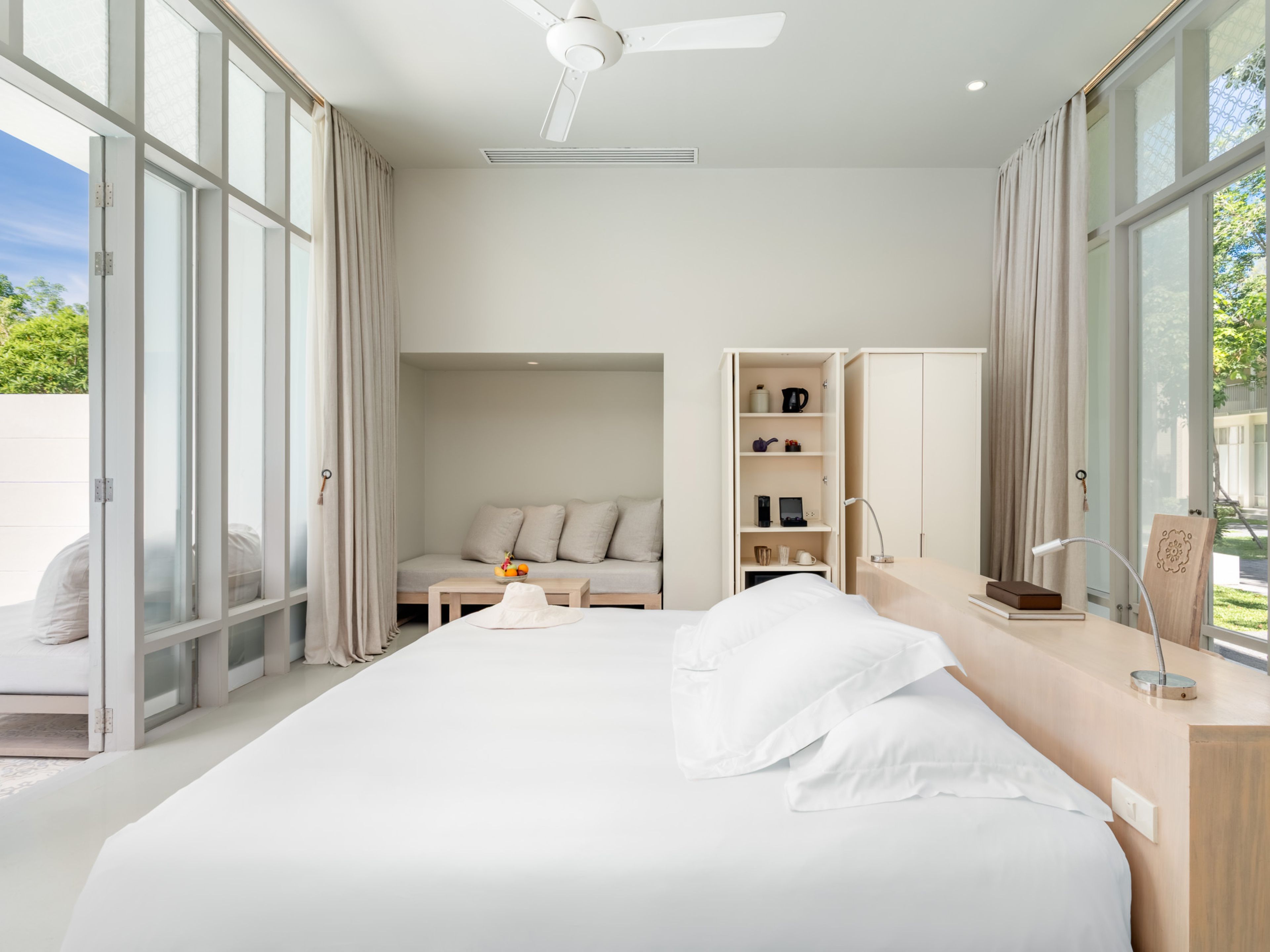 Quarto de hotel moderno com uma cama grande, área de estar com uma mesa e um guarda-roupa.