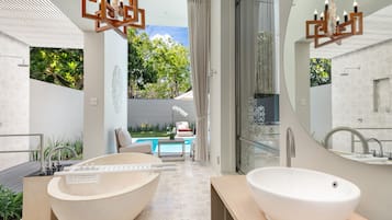 Uma casa de banho moderna com uma grande lavatório embutido, uma banheira independente e zona de duche com vedação em vidro.