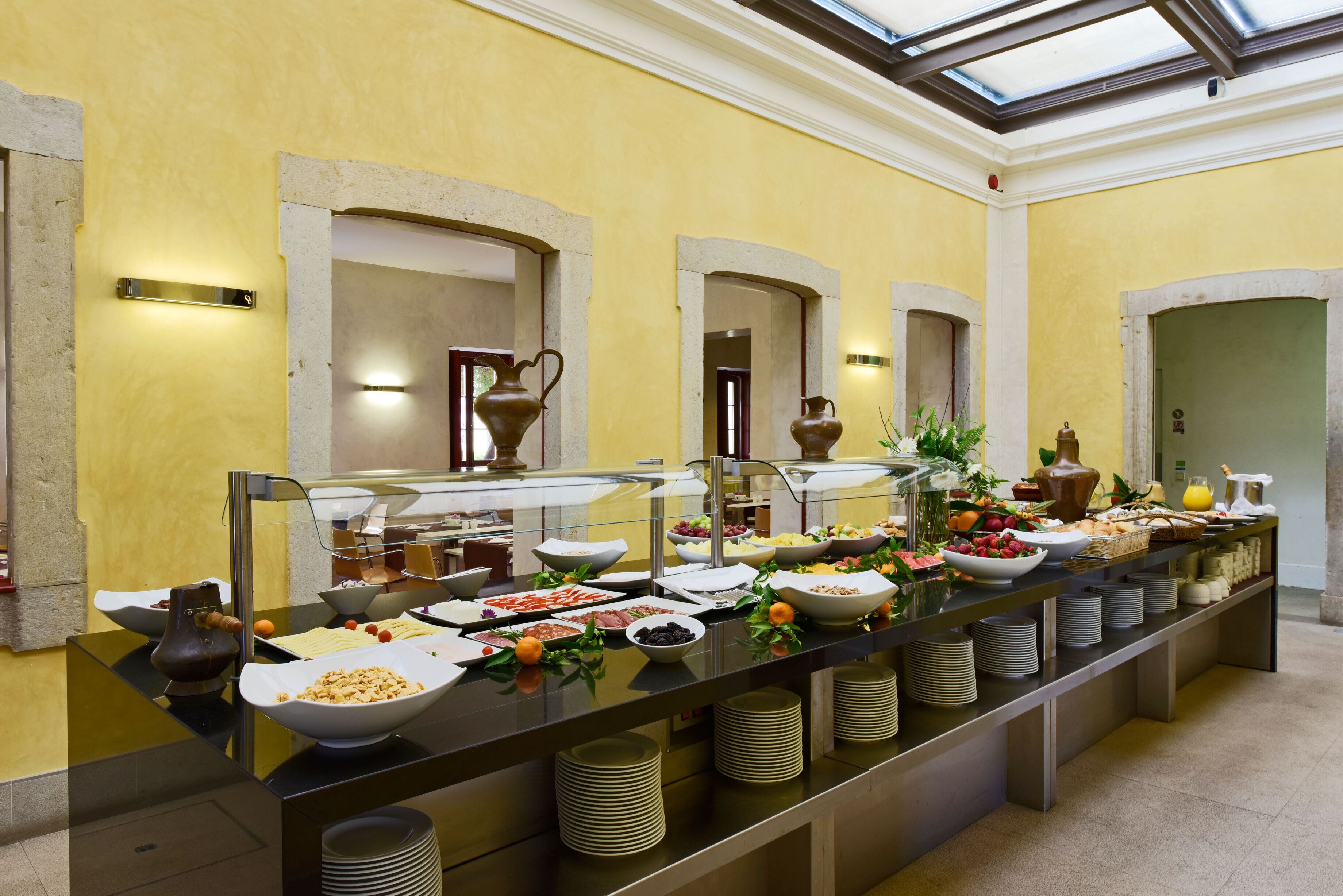 Disposição de buffet com diversos alimentos e uma vitrine de vidro.