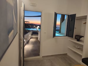 Corredor que dá para uma varanda com vista para o pôr do sol, uma porta e uma estante com um rádio.