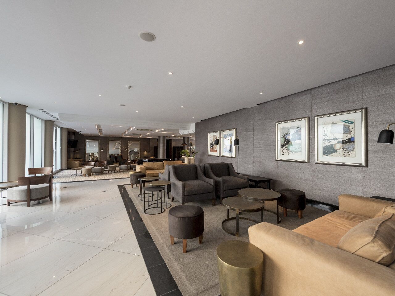 Um hall amplo com design moderno, com diferentes áreas de estar, um bar e um espaço para refeições.