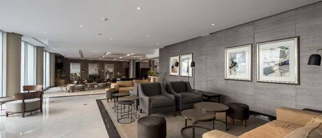 Um hall amplo com design moderno, com diferentes áreas de estar, um bar e um espaço para refeições.