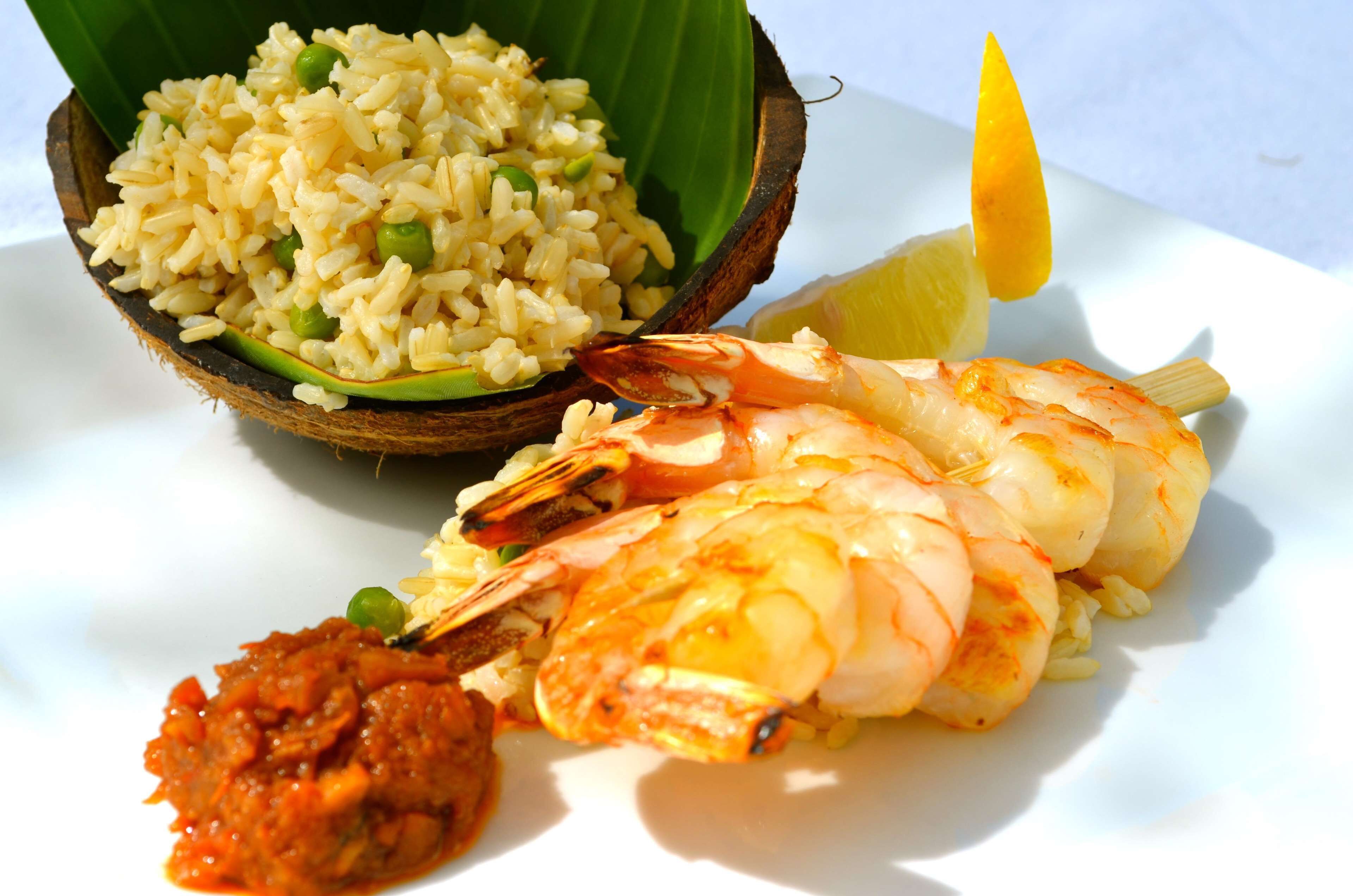 Um prato de arroz, camarão e um acompanhamento de molho.