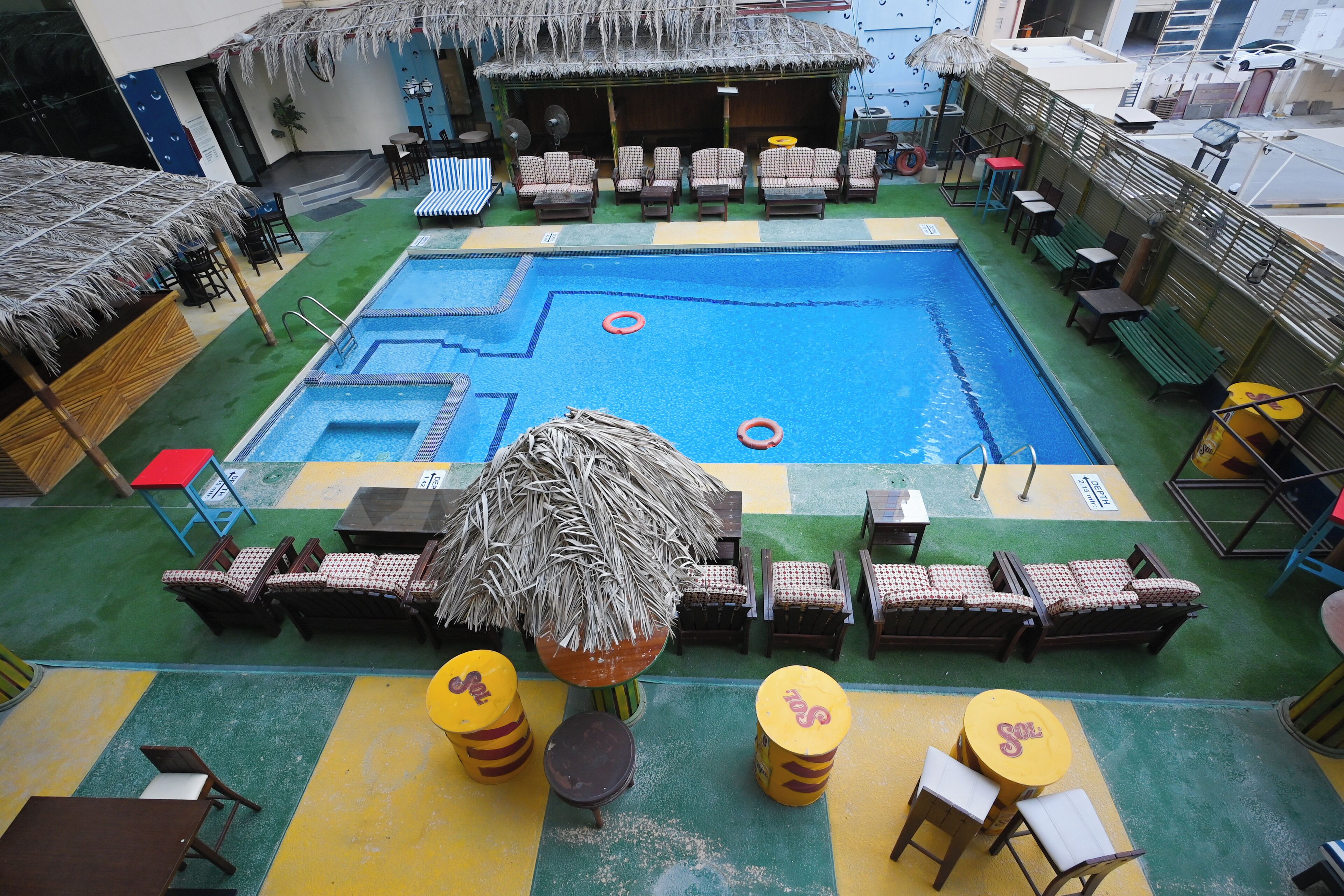 Área de piscina no terraço, com piscina central, espreguiçadeiras e mesas.