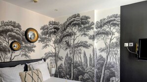 Quarto com cama, bandeja de frutas e painel decorado com um mural de árvore.