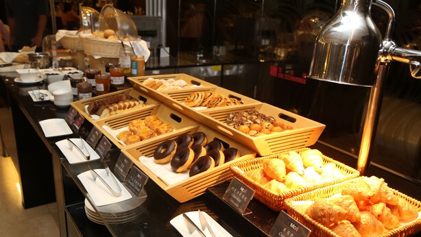 Buffet com diversos alimentos, incluindo doces e donuts.