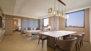 Quarto de hotel moderno com uma grande mesa de jantar, assentos confortáveis, um sofá e vista para a cidade.