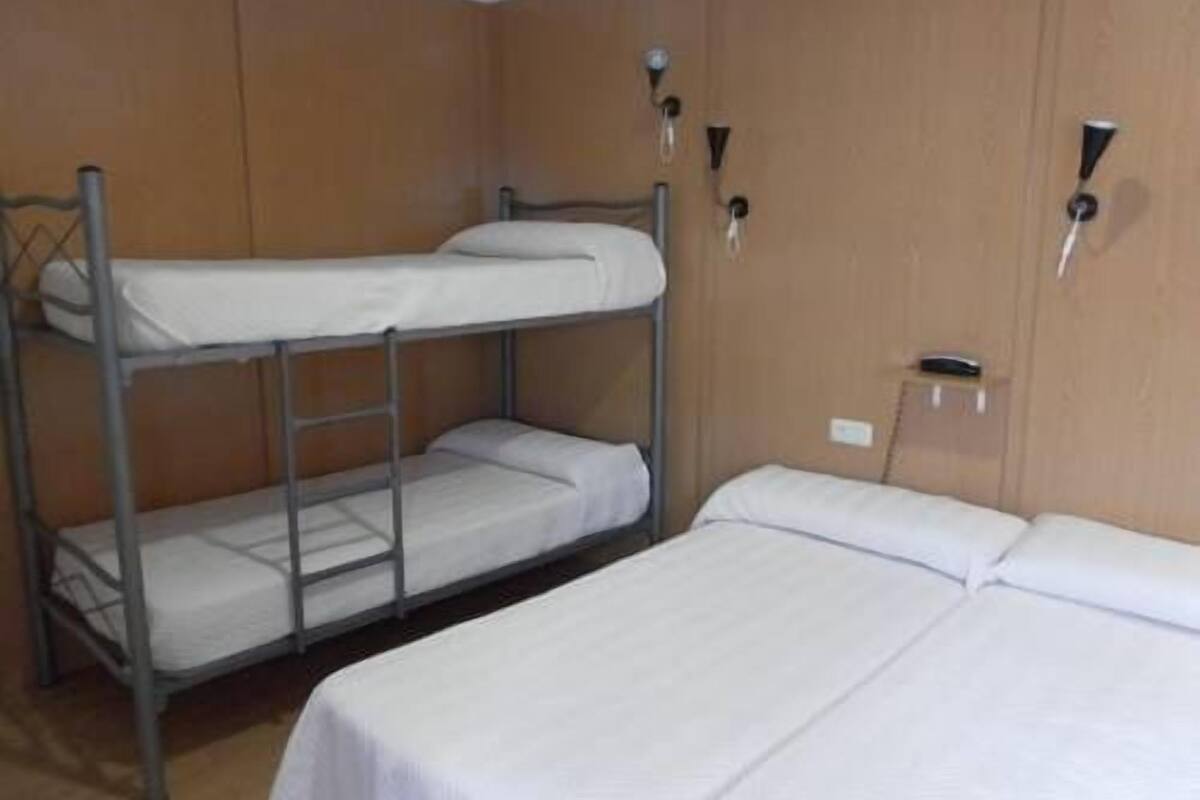 Quarto com beliche, parede de madeira e uma cama individual.