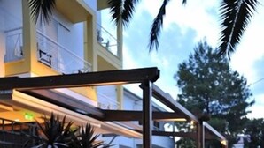 Uma área de refeições ao ar livre com mesas e cadeiras, um candeeiro e um edifício ao fundo.