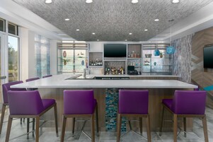 Cozinha moderna com uma ilha grande, banquetas roxas e diversos eletrodomésticos.