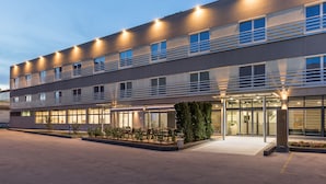 Um hotel moderno com vários andares, janelas amplas e área externa para sentar.