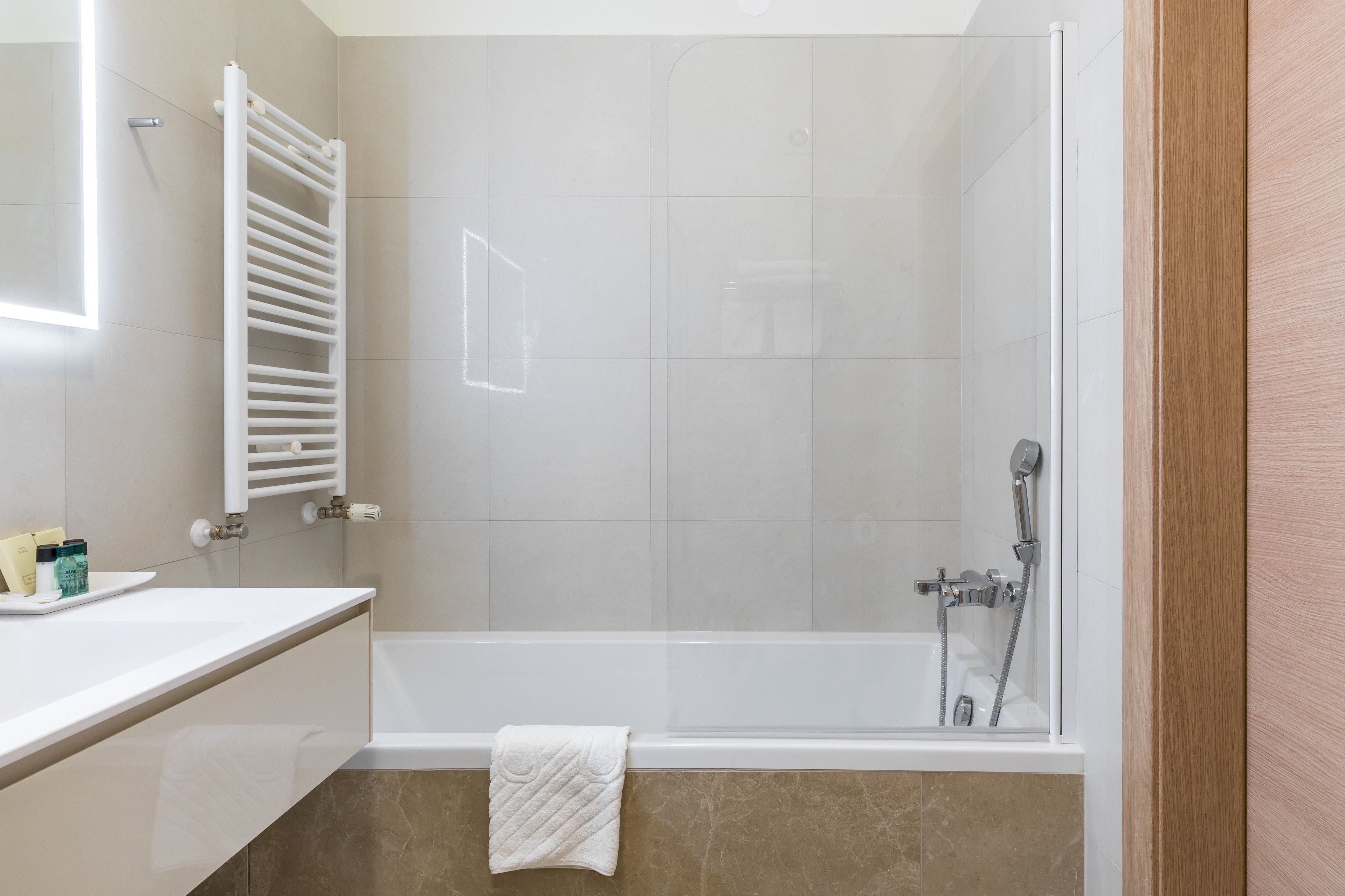 Uma casa de banho moderna com chuveiro envolto em vidro, uma pia branca e um porta-toalhas.