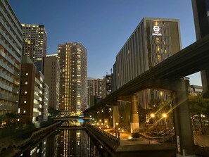 Um hotel moderno com uma placa grande, cercado por edifícios altos e uma ponte.