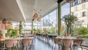 Uma ampla sala de jantar coberta, com pé-direito alto, janelas grandes e mobiliário moderno.