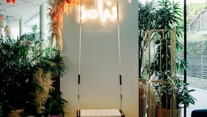 Interior moderno com uma cadeira balanço suspensa, plantas em vasos e um letreiro de neon.