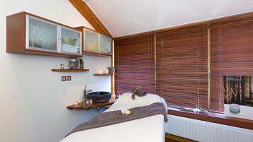 Um quarto com cama, janela com persianas, prateleira com uma tigela e armário com portas de vidro.