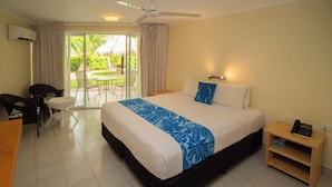 Quarto de hotel com cama, escrivaninha, cadeira, mesa de cabeceira e vista para o exterior.
