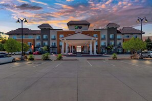 Um hotel com entrada central, várias varandas e estacionamento.