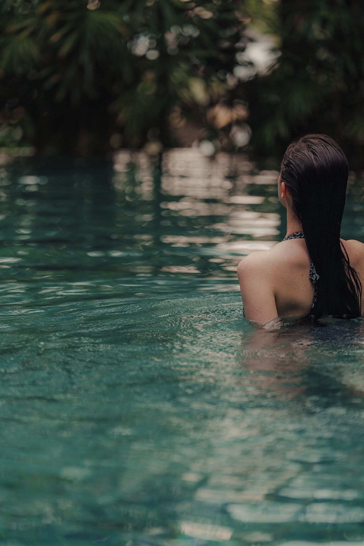 Uma pessoa em uma piscina, com um fundo natural desfocado.