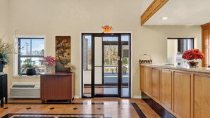 Cozinha moderna com armários de madeira, piso de mármore e vista pela porta de vidro.