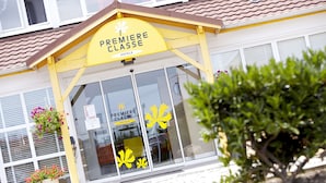 Entrada de hotel com toldo amarelo e placa com a inscrição 'PREMIERE CLASSE HOTELS'.