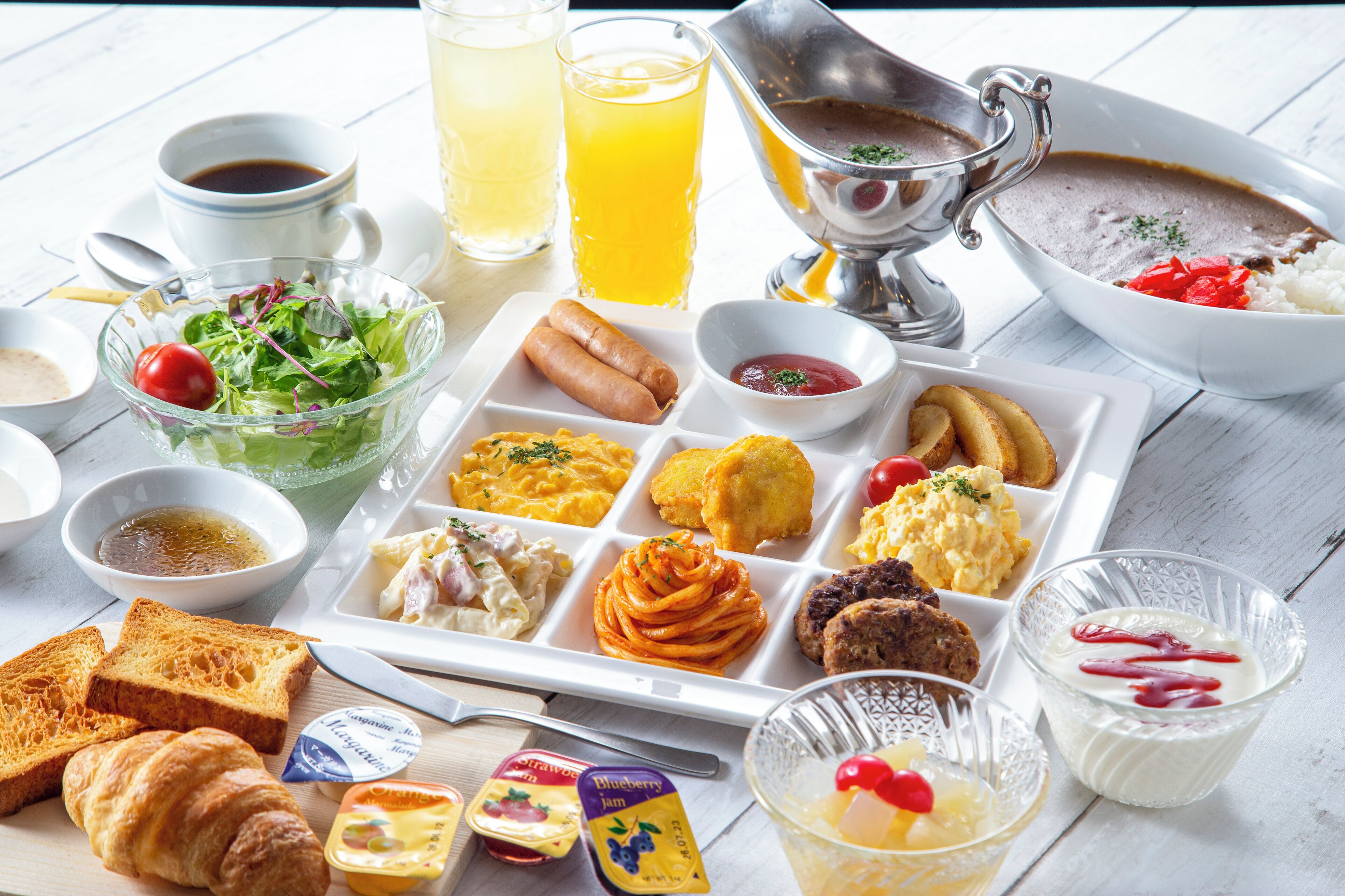 Uma bandeja de café da manhã com diversos alimentos, bebidas e acompanhamentos.