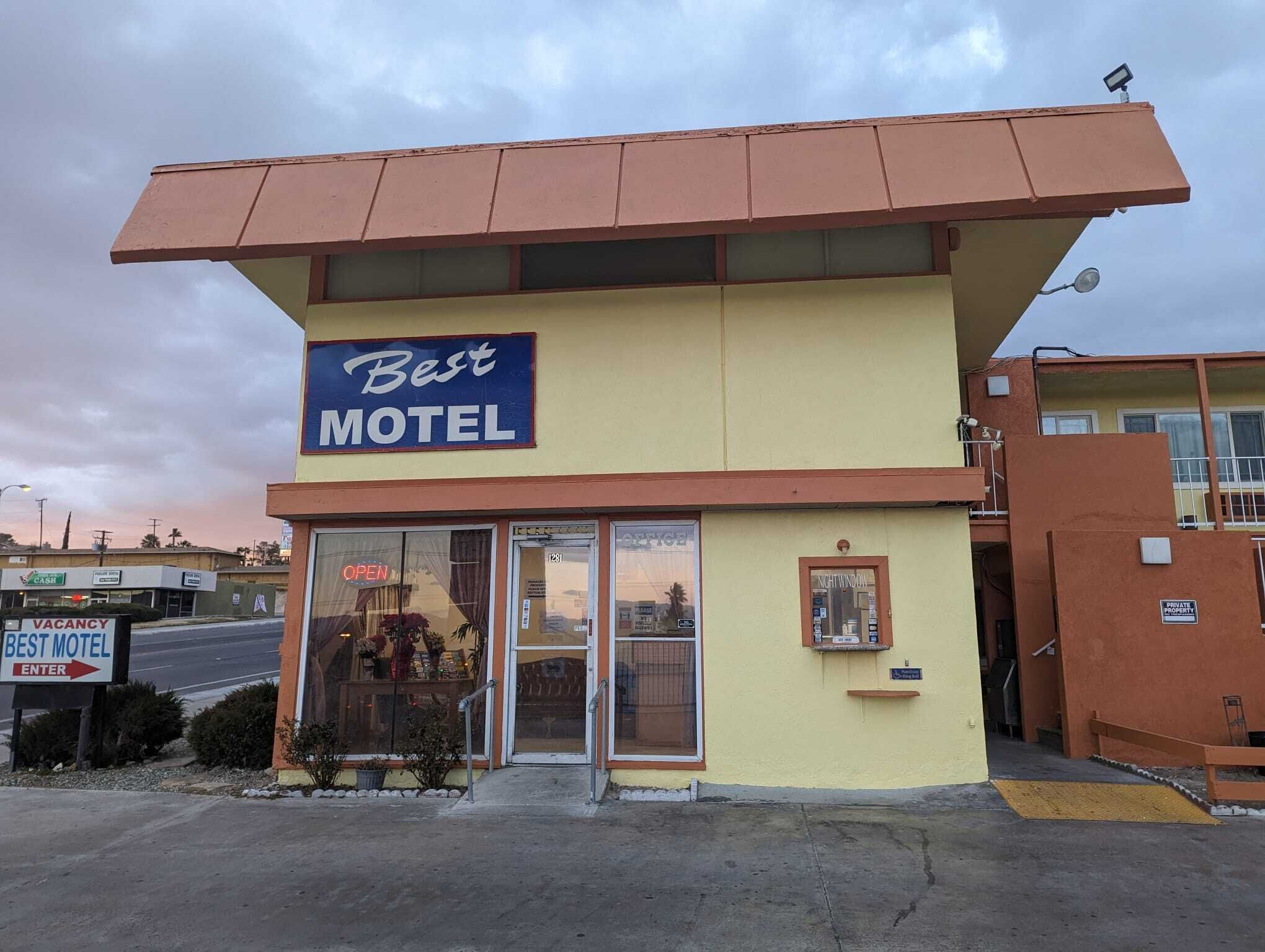 Um motel com uma placa indicando "Best MOTEL" e uma placa de "VACANCY" abaixo.