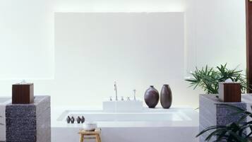 Um banheiro moderno com banheira, dois vasos, um banquinho e uma planta em vaso.