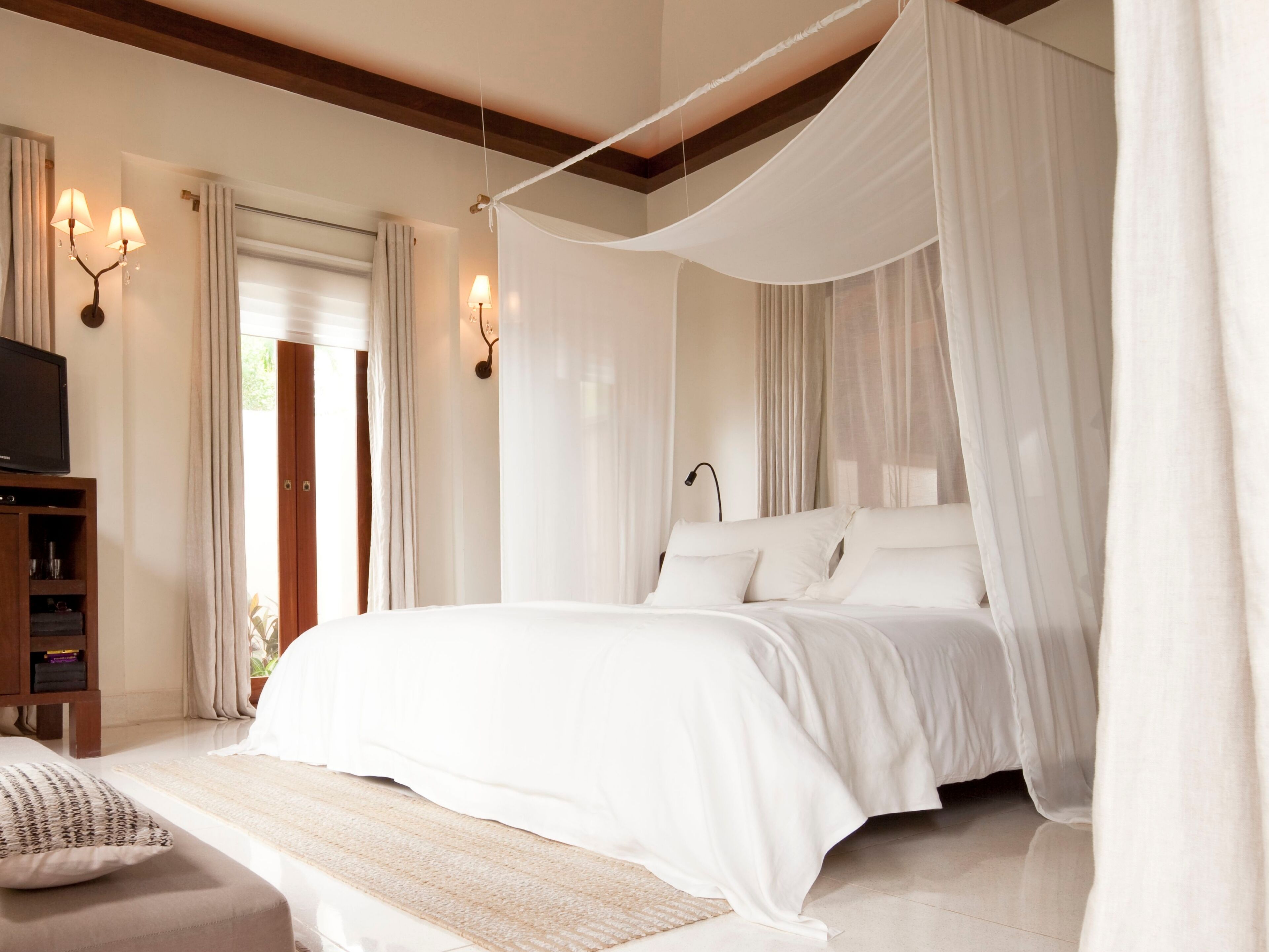 Quarto com uma cama grande, televisão em um armário de madeira e janela com cortinas.